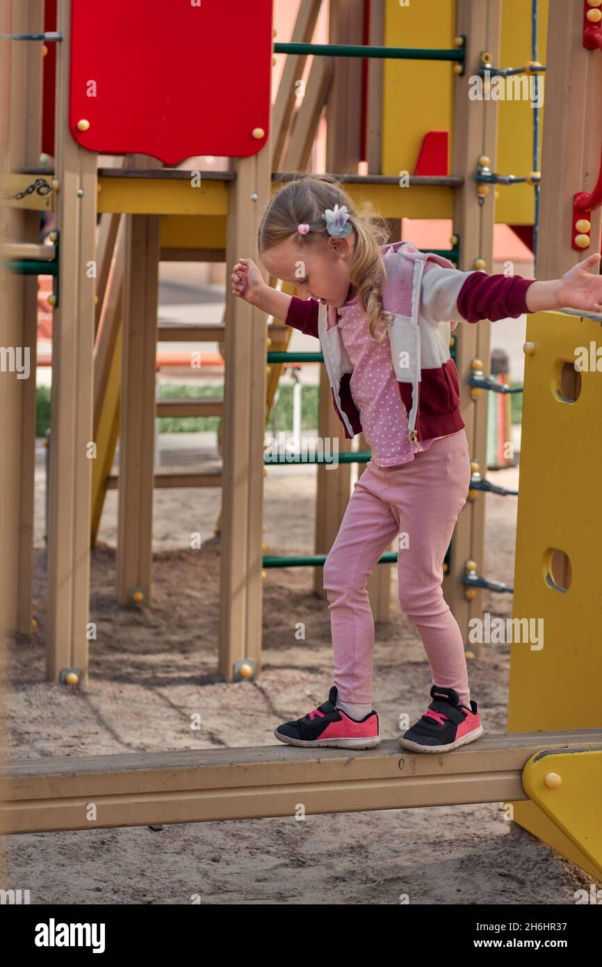 Kids play on the playground. Happy laughing girl have fun swinging and ...