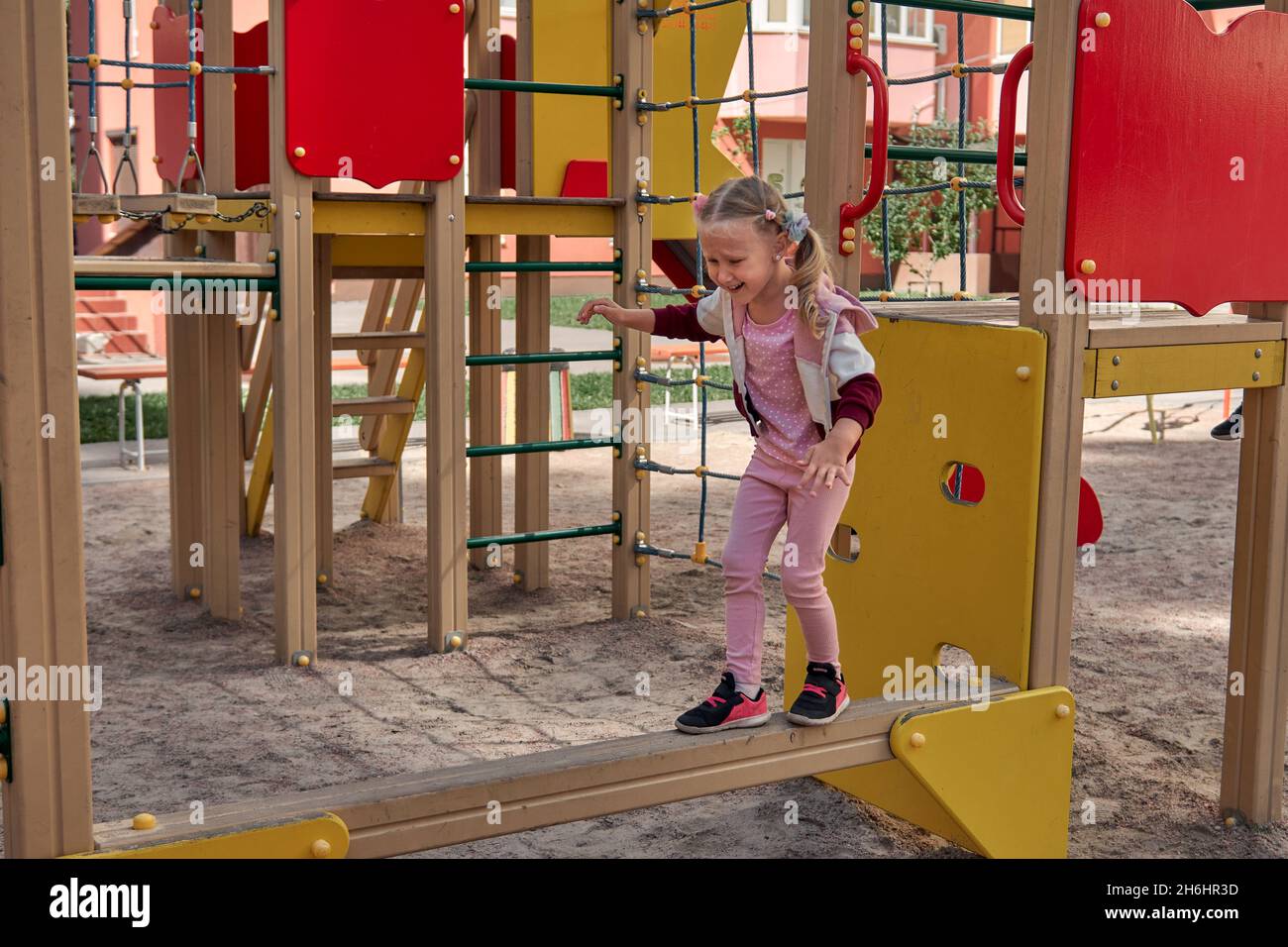 Kids play on the playground. Happy laughing girl have fun swinging and ...