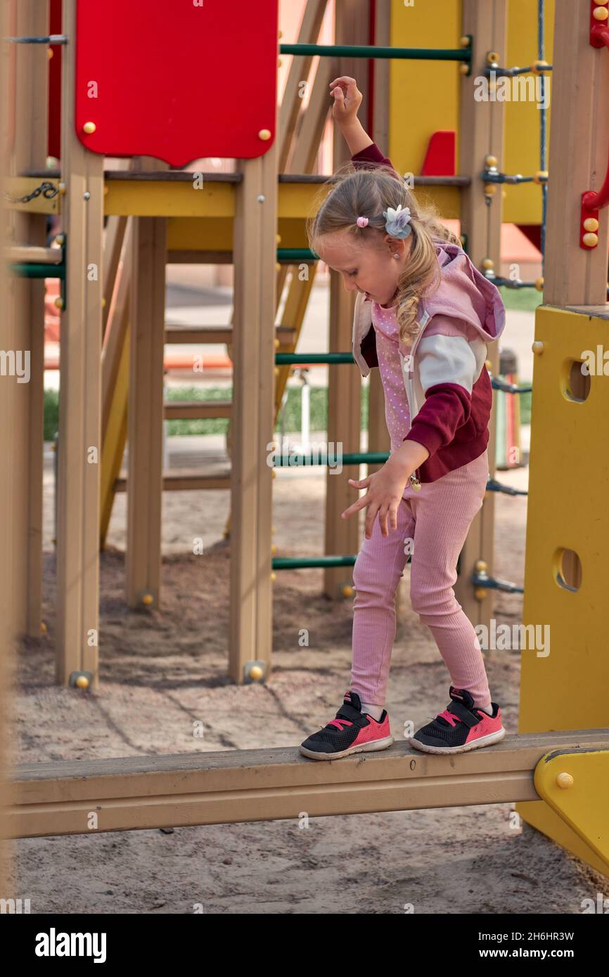 Kids play on the playground. Happy laughing girl have fun swinging and ...