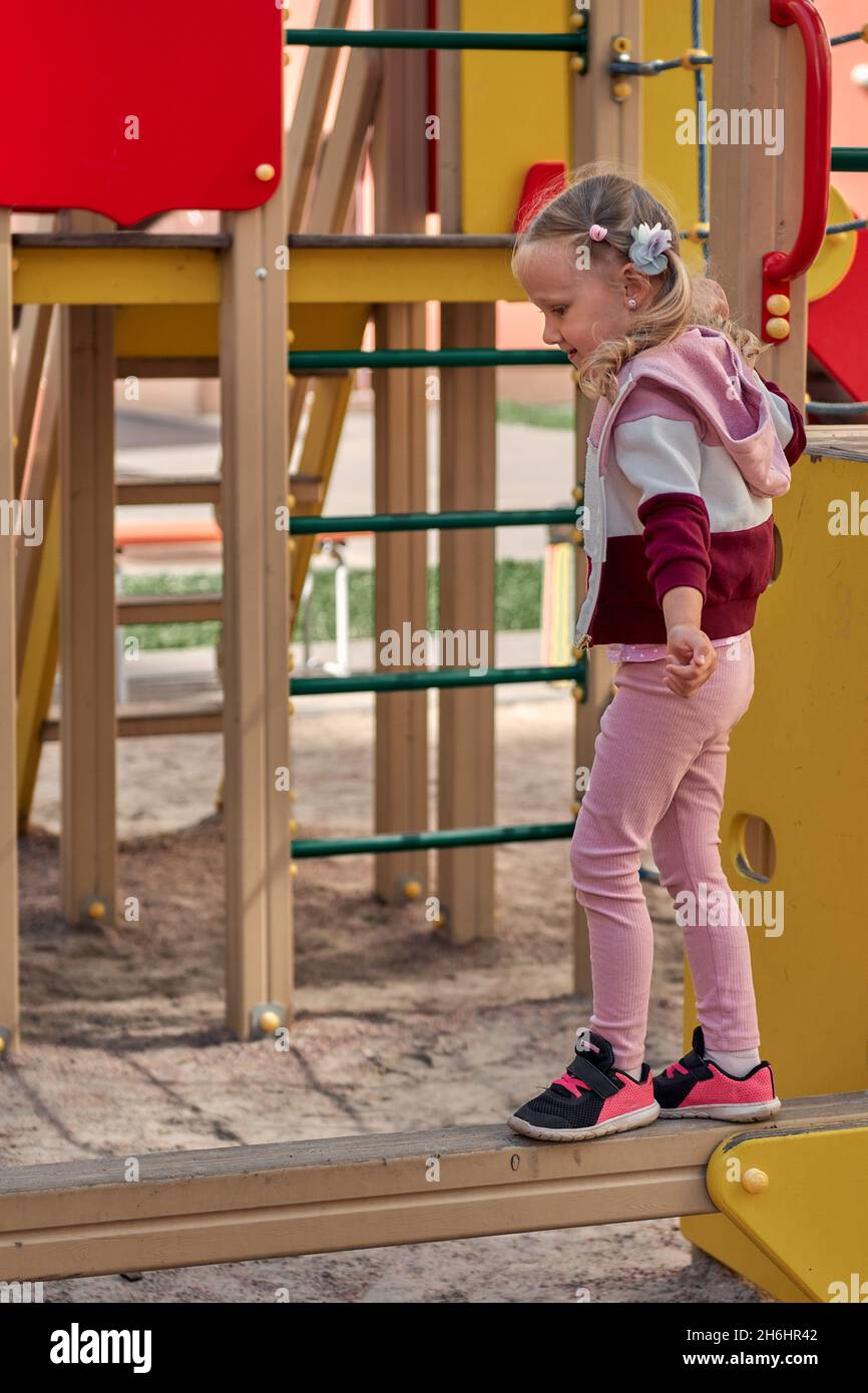 Kids play on the playground. Happy laughing girl have fun swinging and ...