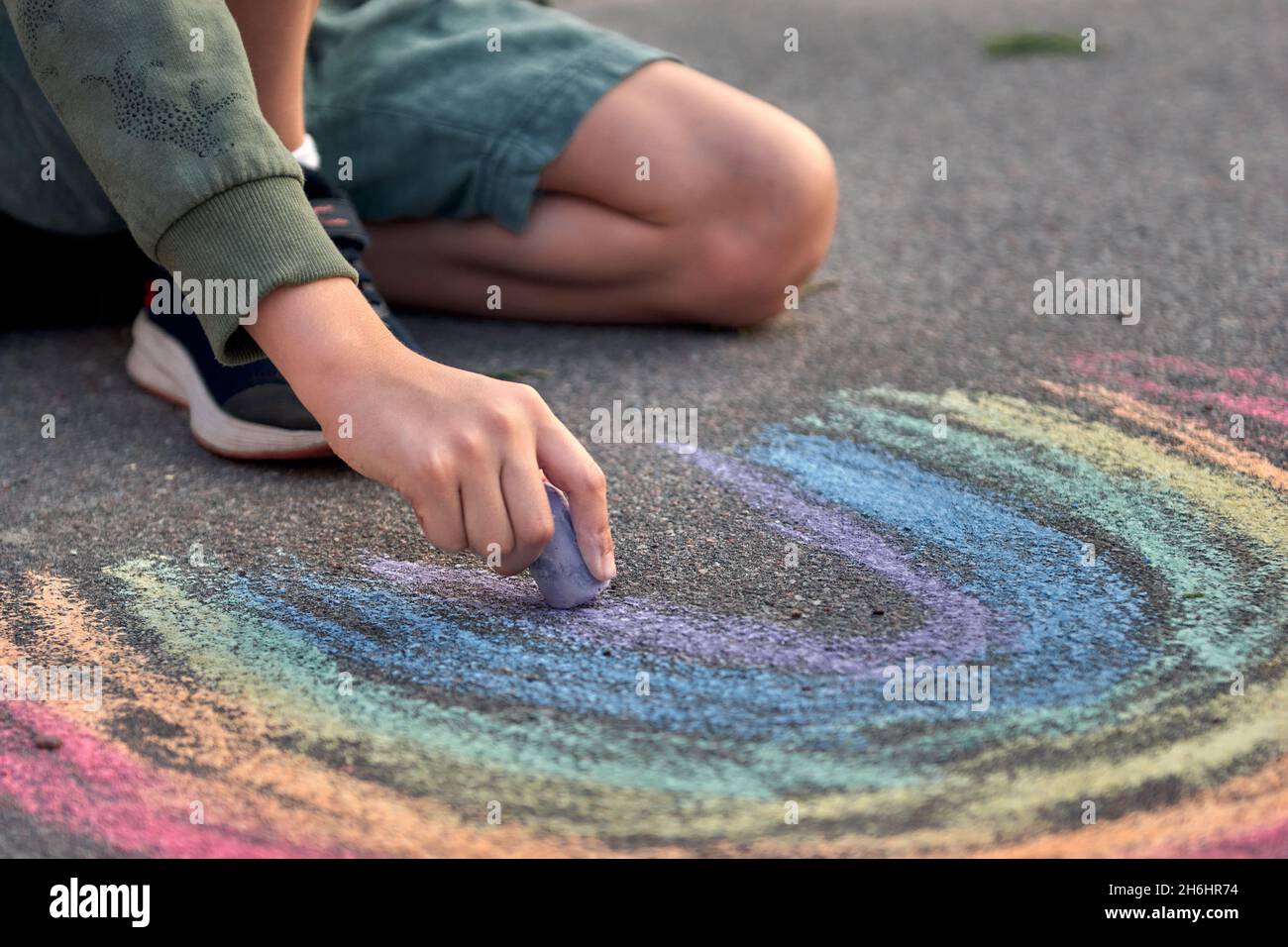 Kids paint outdoors. Portrait of a child boy drawing a rainbow colored ...