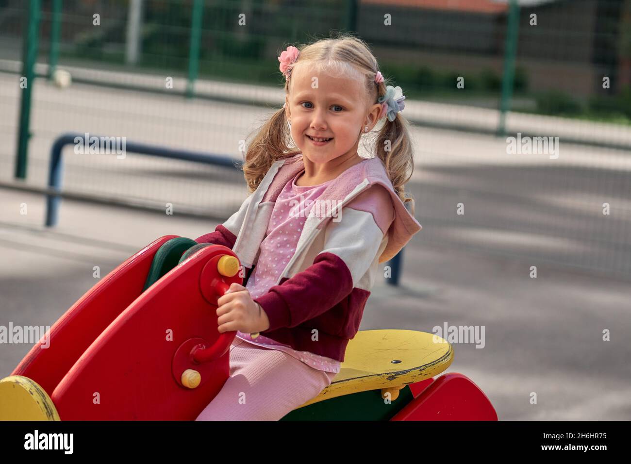 Kids play on the playground. Happy laughing girl have fun swinging and ...