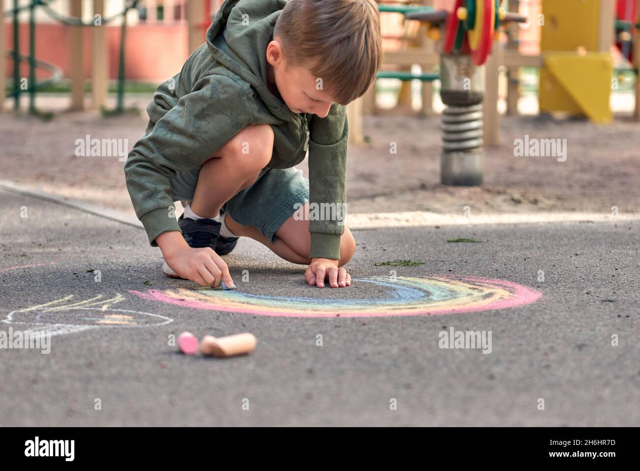 Kids paint outdoors. Portrait of a child boy drawing a rainbow colored ...