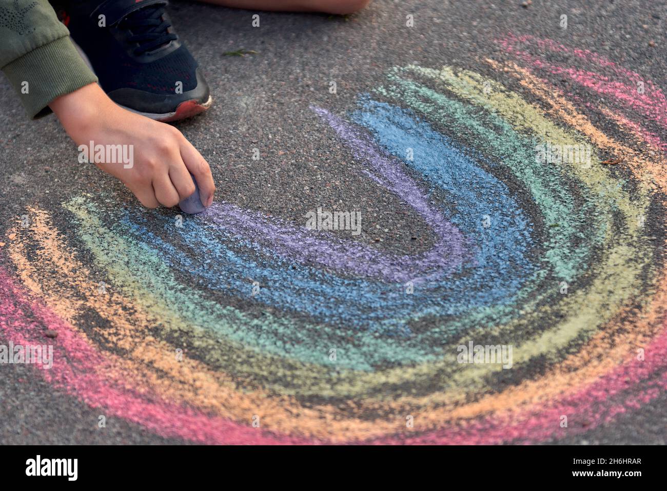Kids paint outdoors. Portrait of a child boy drawing a rainbow colored ...