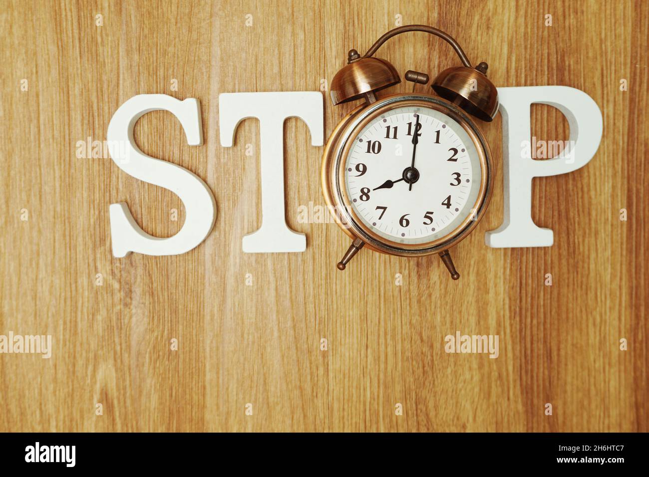 Stop Word and Alarm Clock on wooden background Stock Photo - Alamy