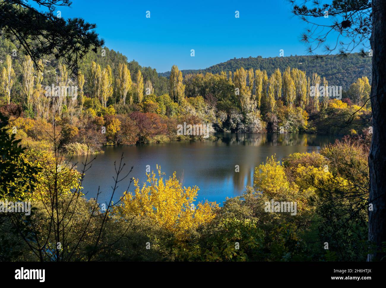 A calm blue lake with landscape of hills and forest in intense fall ...