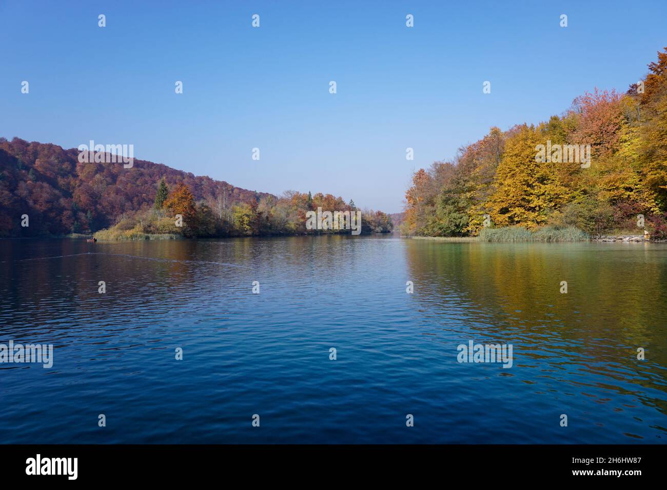 landscape view of calm blue lake with reflections of hills and forest ...