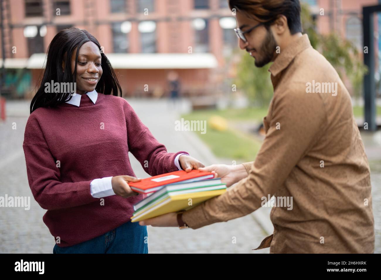 Indian man giving books to black girl outdoors Stock Photo - Alamy