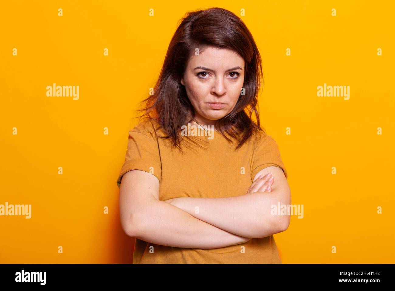 Upset woman standing with crossed arms in studio, showing disapproving ...