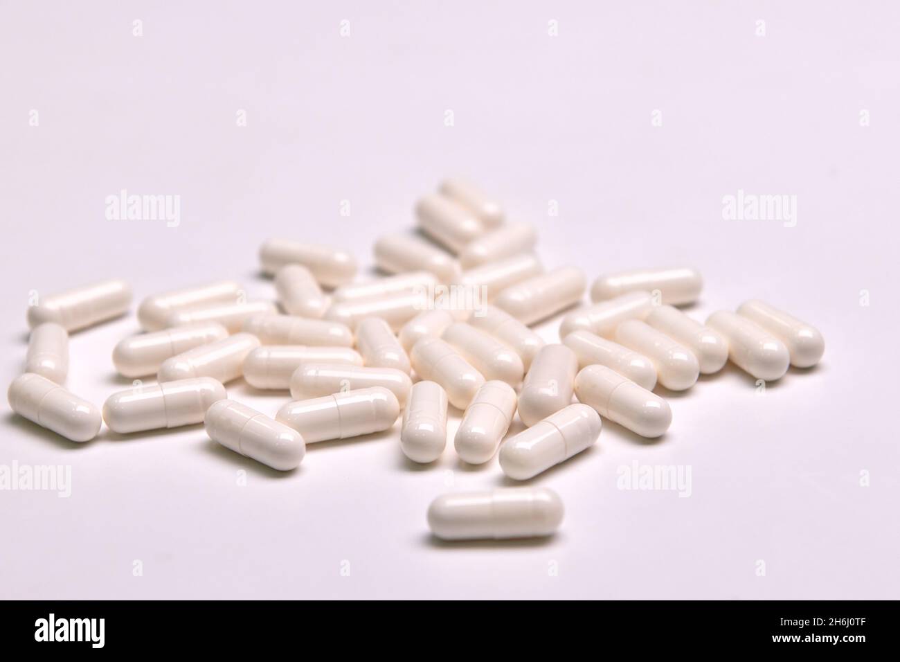 Many white capsule pills on a colorful background. Supplements and ...