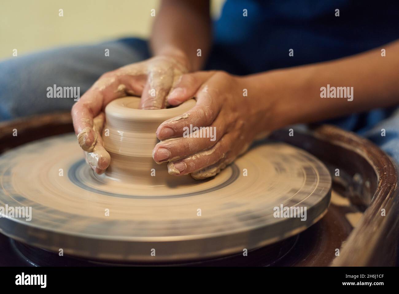 Hands of young craftsperson holding by rotating pottery wheel while ...