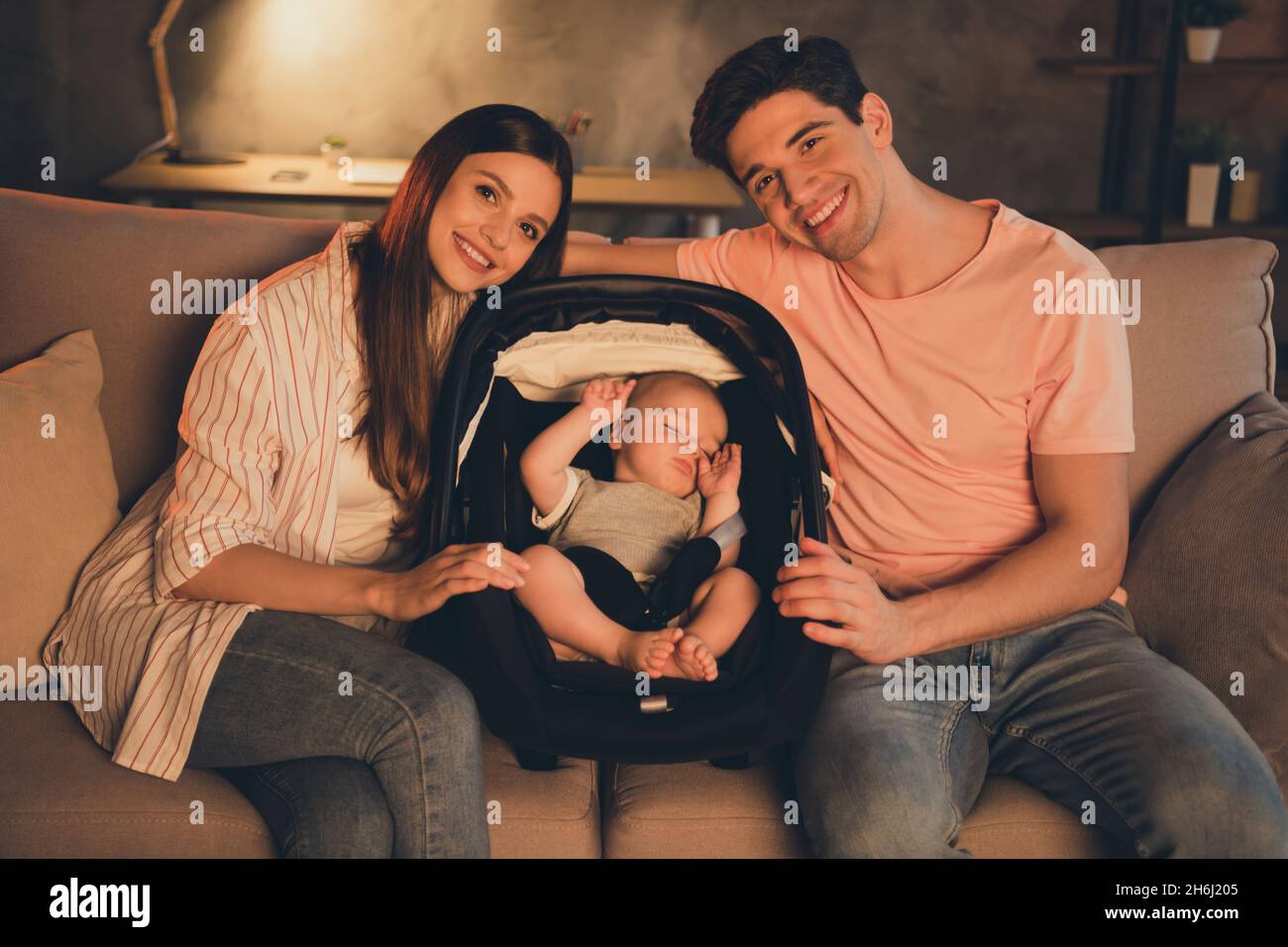 Portrait of attractive careful cheerful couple rocking baby in chair ...
