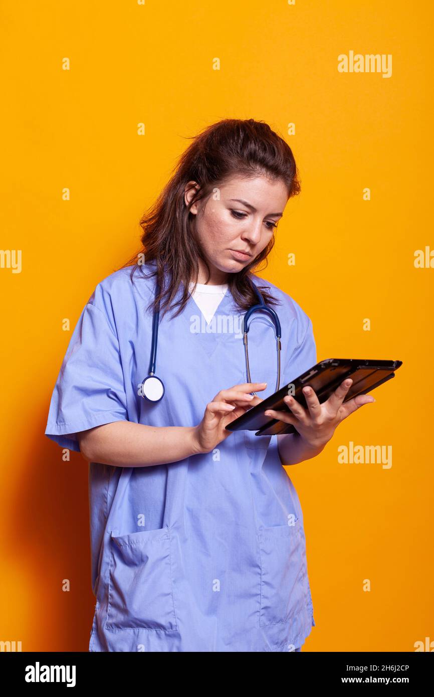Woman nurse working with digital tablet while wearing uniform and ...
