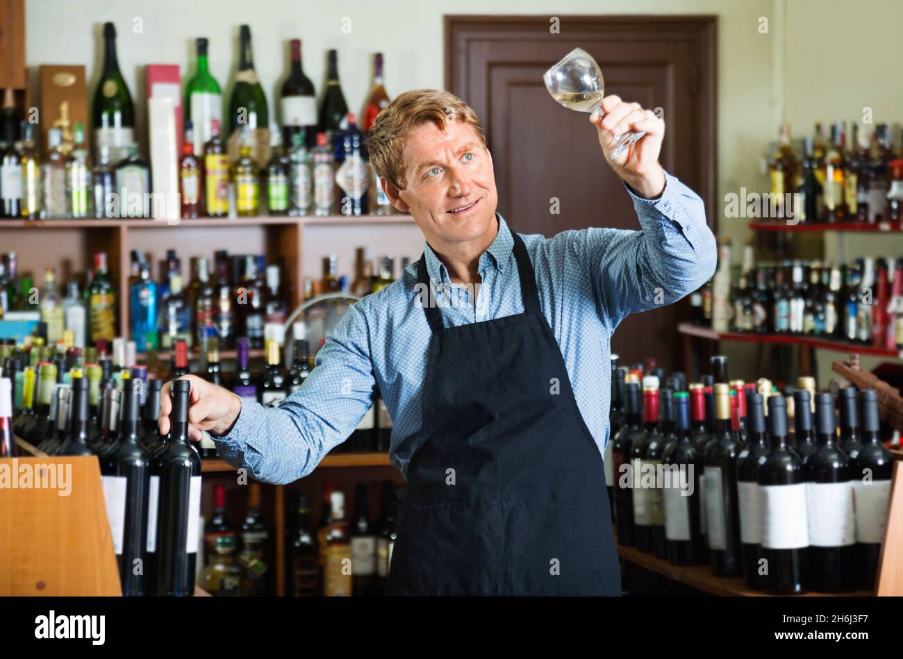 Man working in wine house holding glass of wine for tasting Stock Photo ...