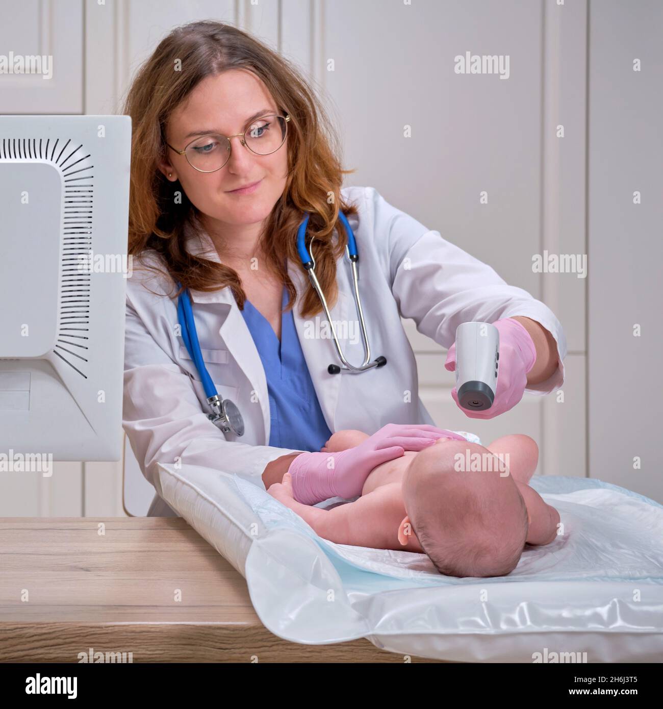 Doctor checks the temperature of the newborn baby with a thermometer. A ...