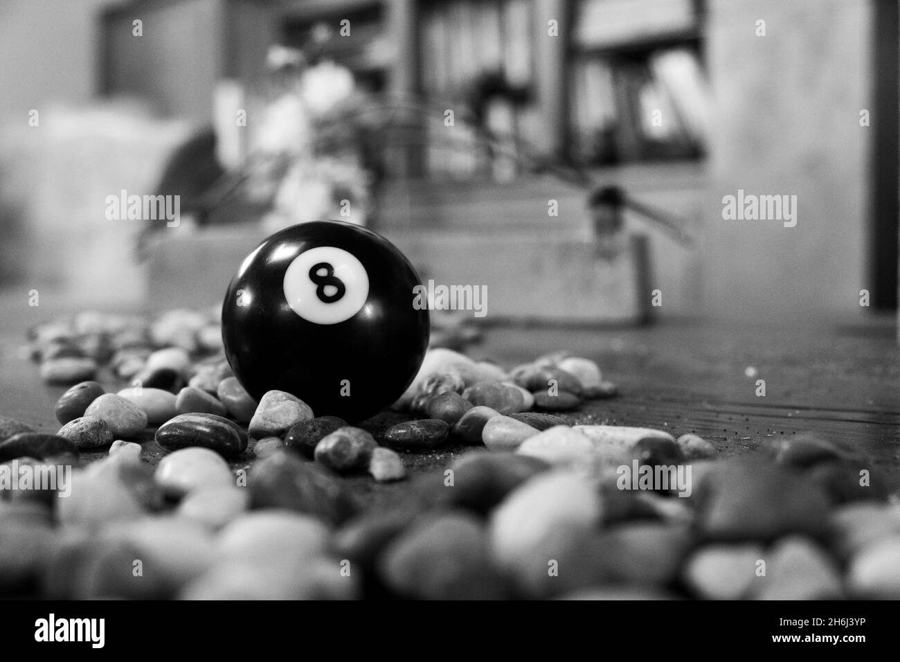 Grayscale shot of a billiard ball number 8 on the floor surrounded by ...
