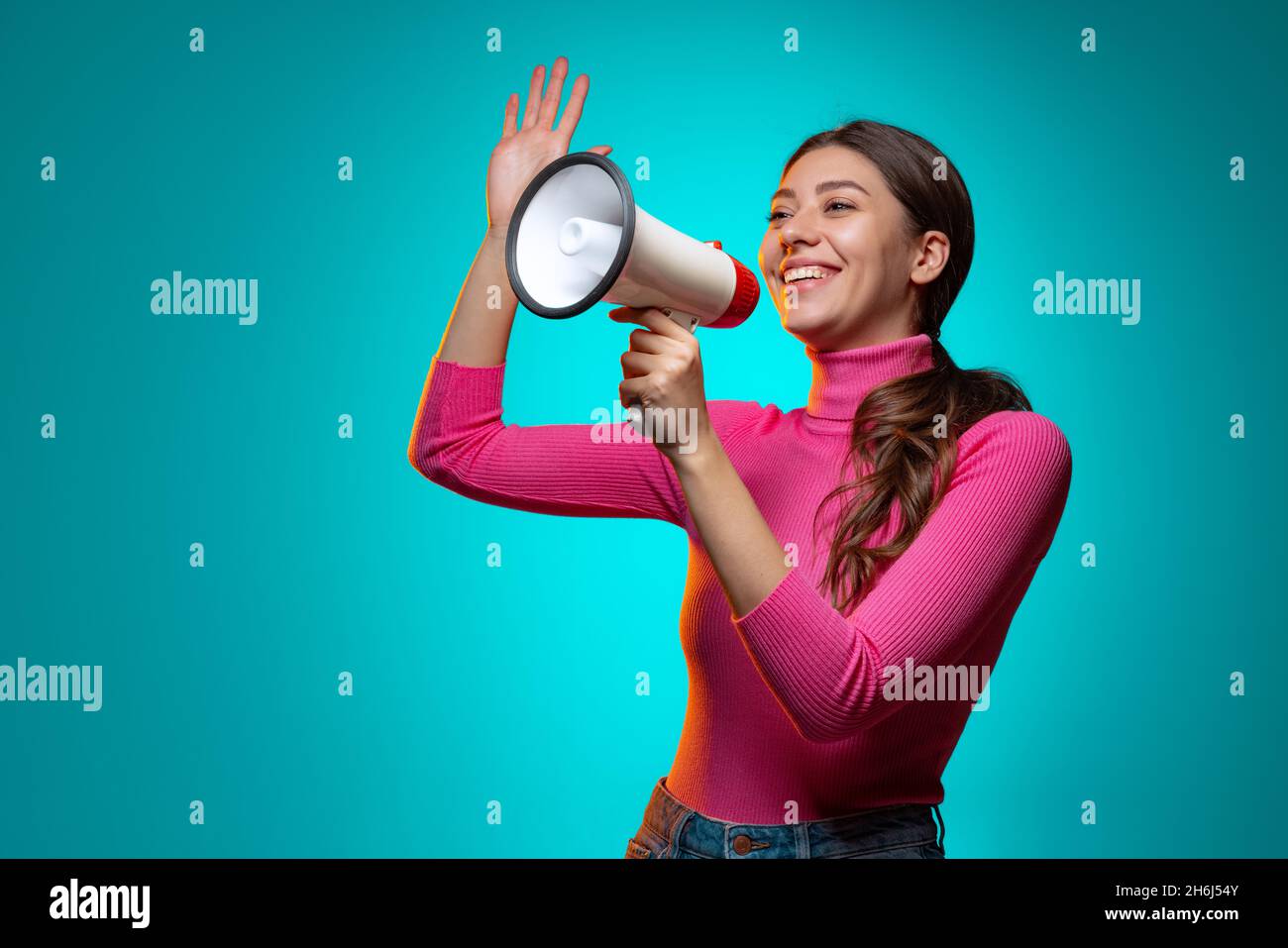 Portrait of young beautiful emotional girl shouting at megaphone ...