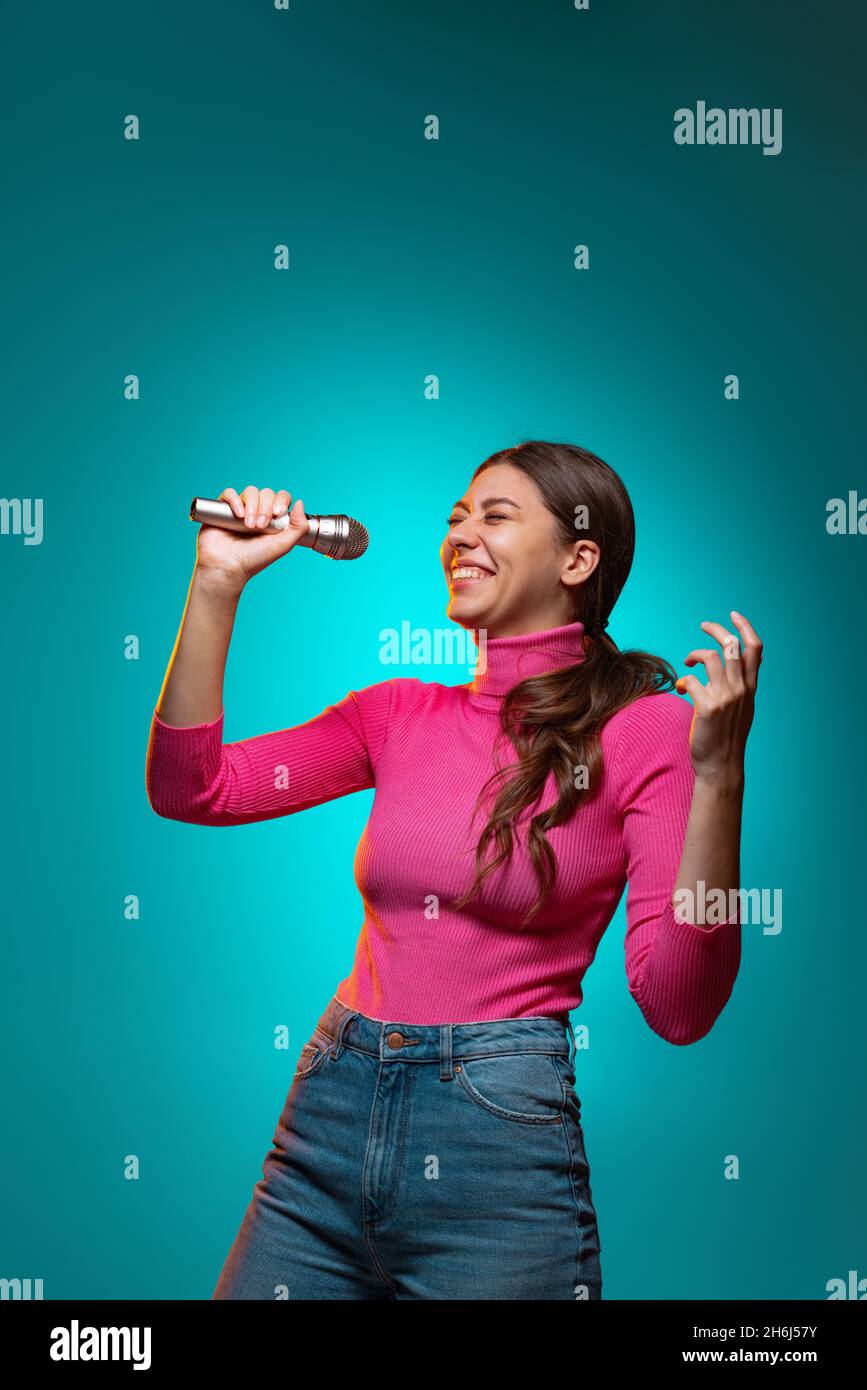 Portrait of young beautiful happy girl singing at microphone isolated ...