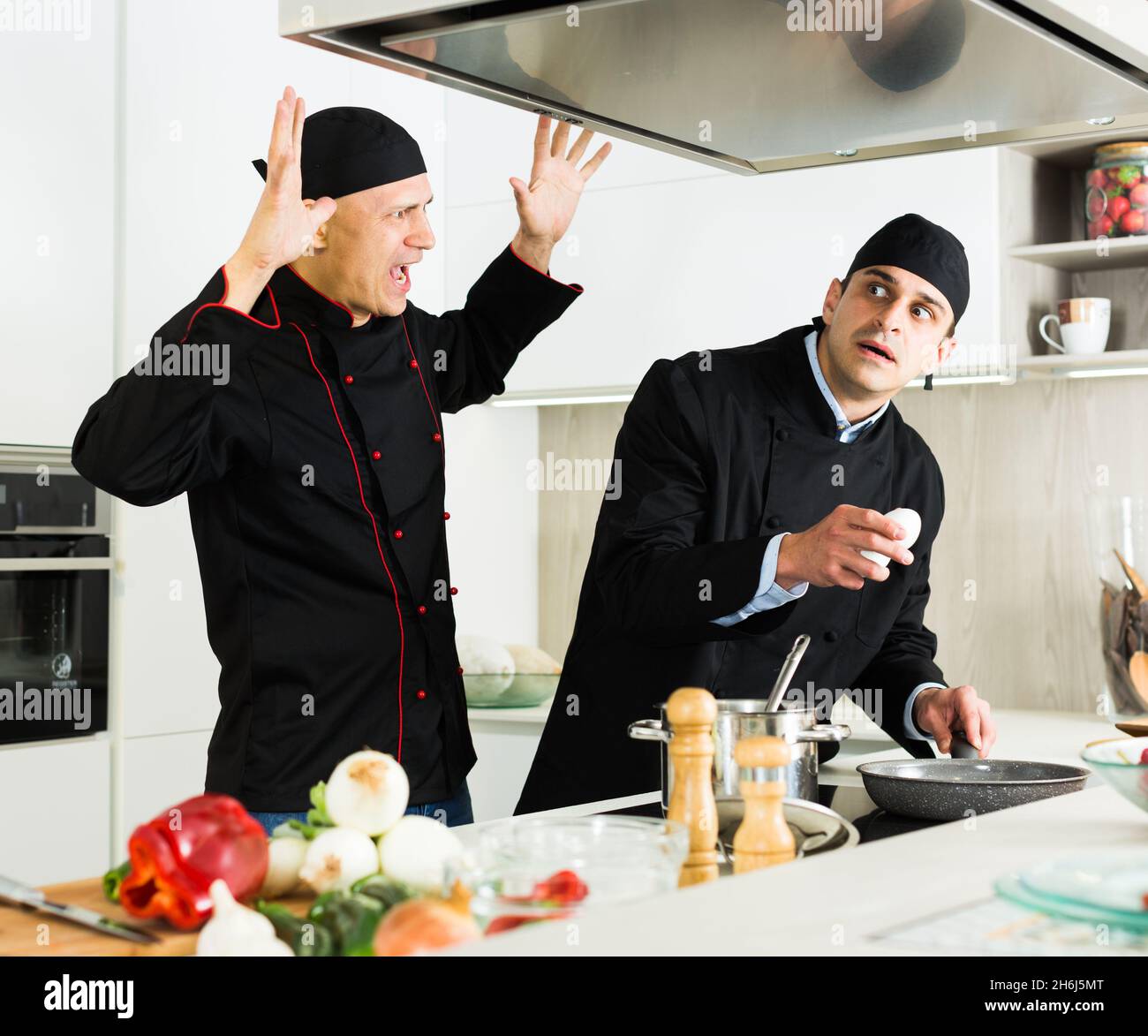 Men chefs in black uniform having conflict on kitchen Stock Photo - Alamy