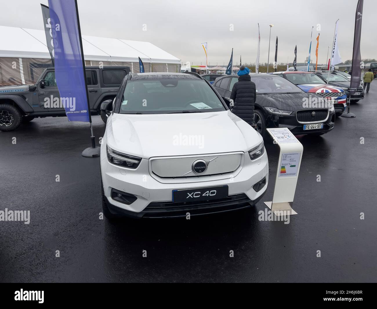woman walking with kid in stroller admiring the new electric car from ...