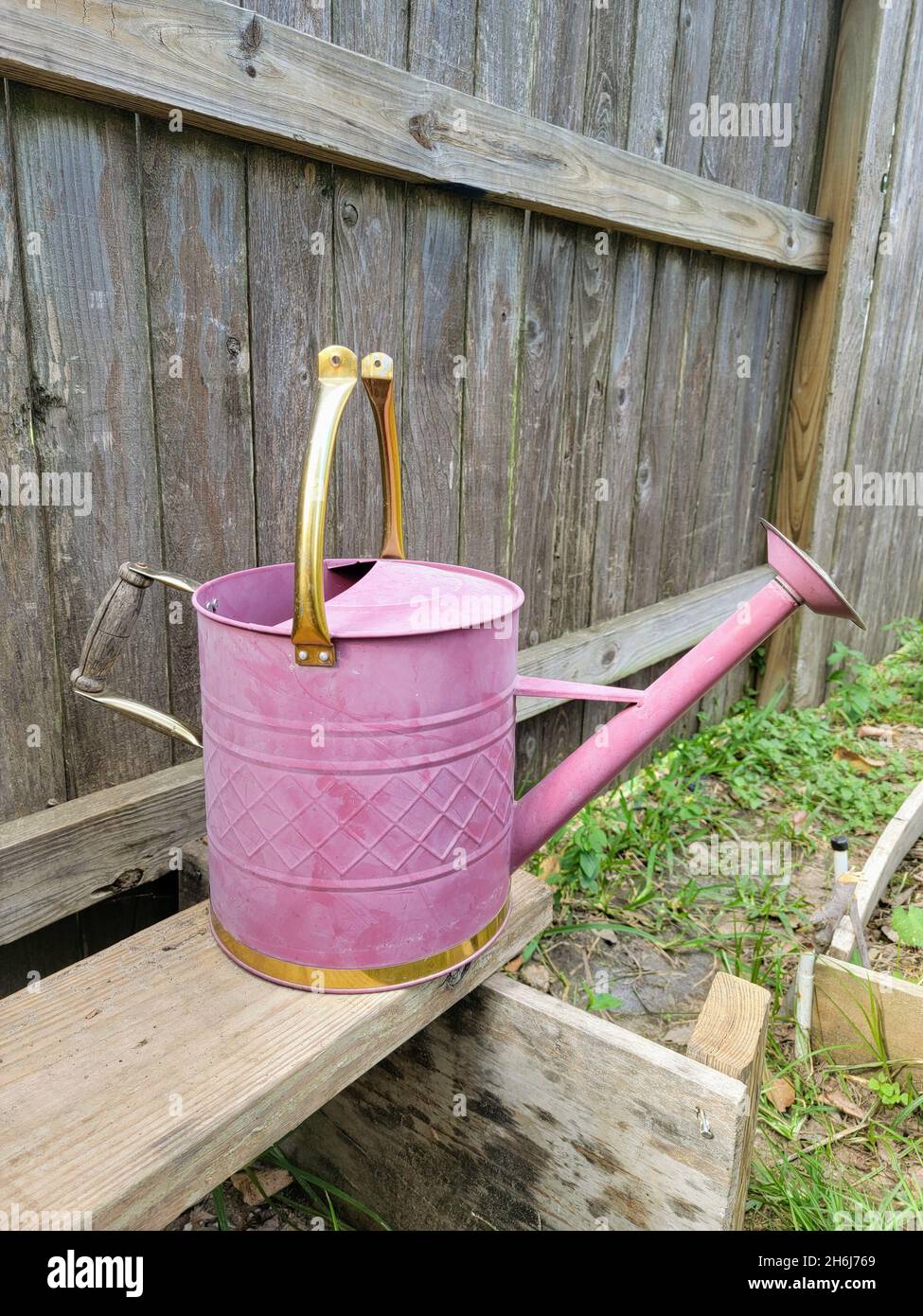 Vertical shot of a broken vintage garden pitcher in pink and golden ...