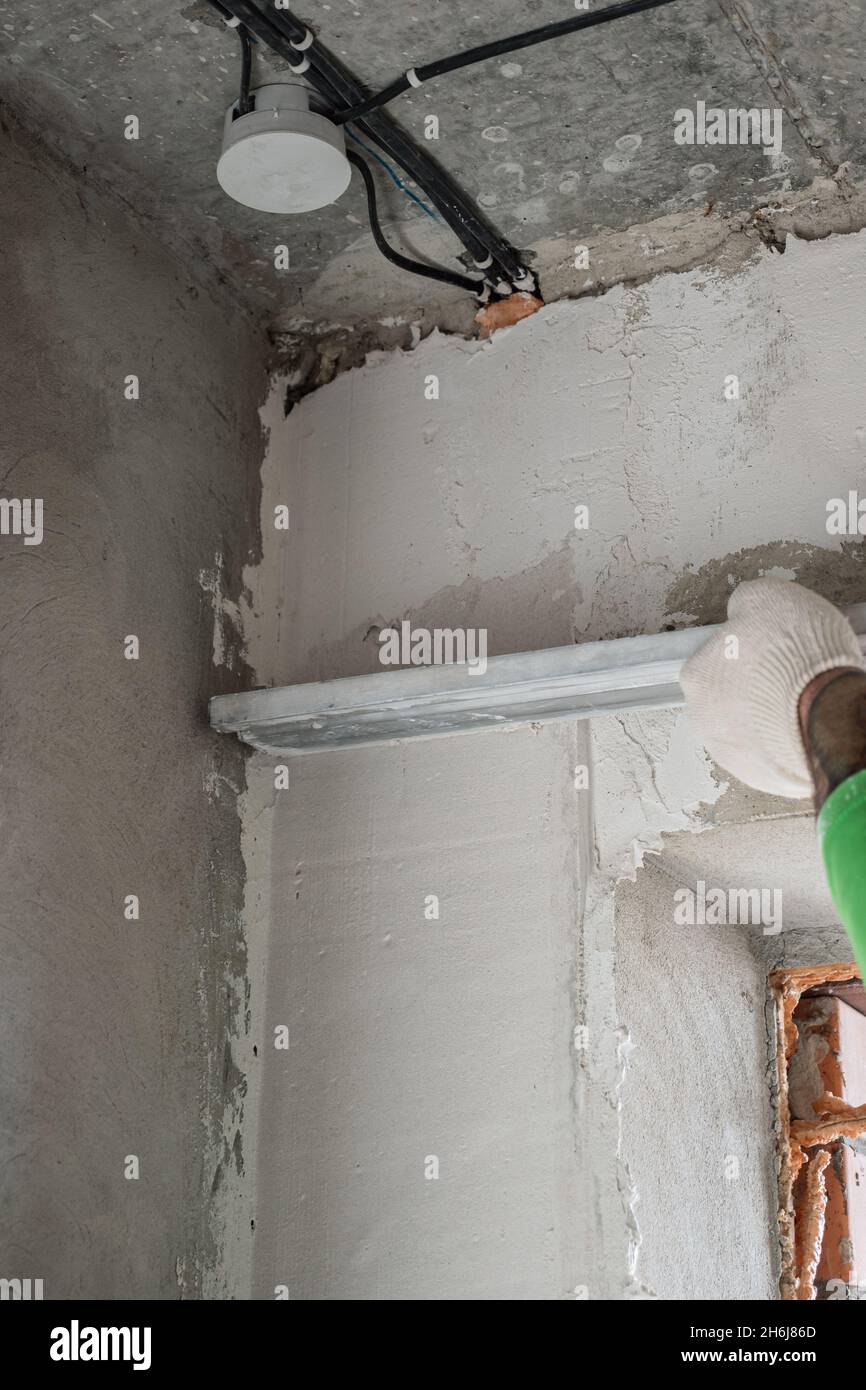 Leveling a newly plastered wall with an aluminum rule. The concept of ...
