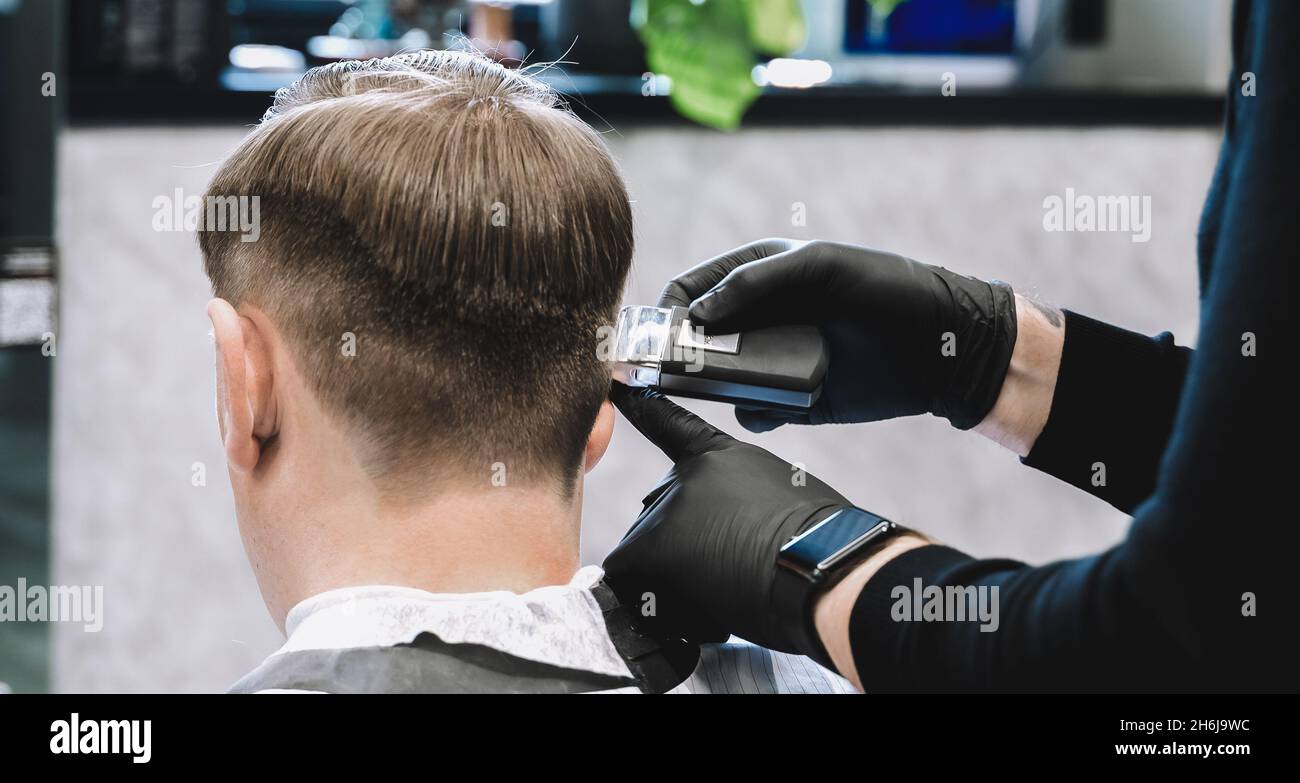 Visit to the barbershop. Hairdresser, barber shaves client's temples ...