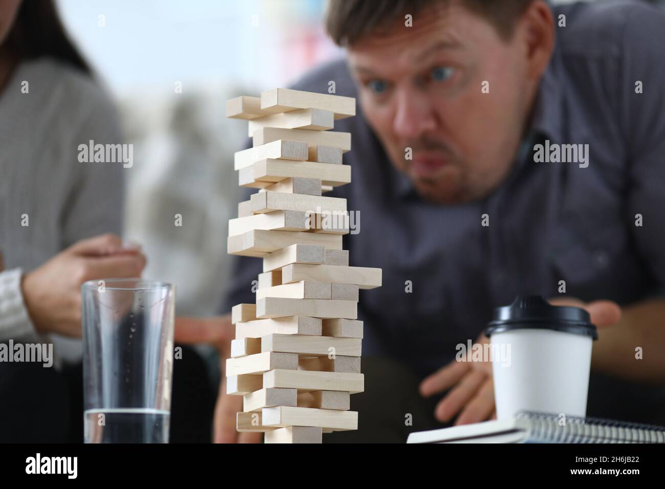 Man assembles a tall tower from wooden rectangular blocks Stock Photo ...