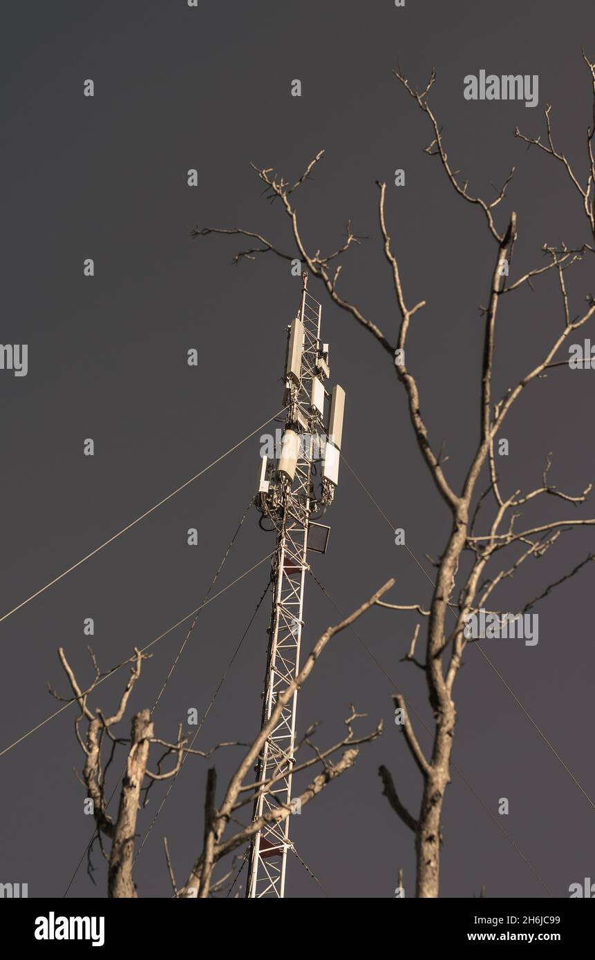A 4G and 5G cellular telecommunication tower against a thundering sky ...