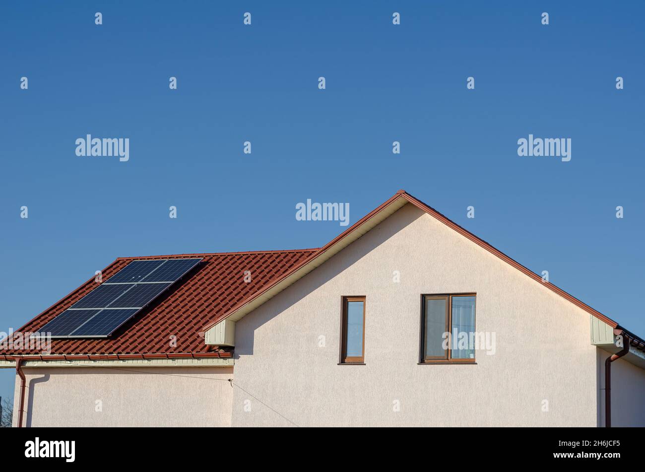 Large two-story cottage or country house against a blue sky. Tile roof ...