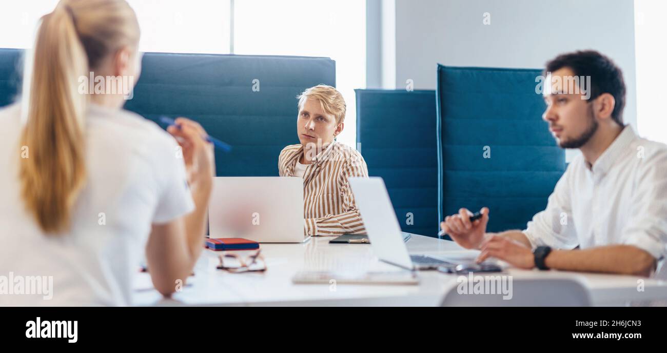 Group of people confer at work sitting at desk Stock Photo - Alamy