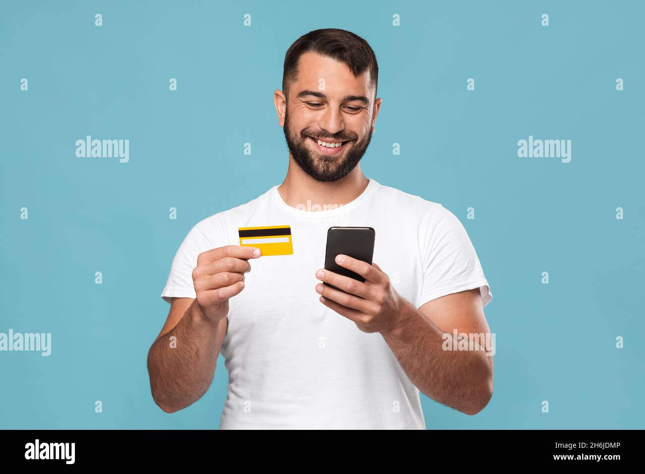 Cheerful middle aged handsome european male orders goods, shows credit ...