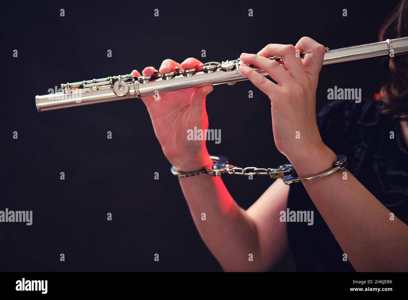 Hands Of A Woman Musician With A Flute In Handcuffed Hands On A Black