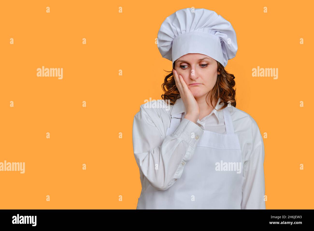 Sad woman chef holding her head on yellow studio background, copy space ...