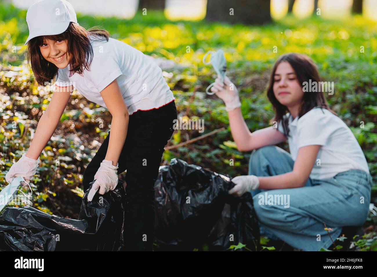 Close up photo of two pretty girls participate in gathering the rubbish ...