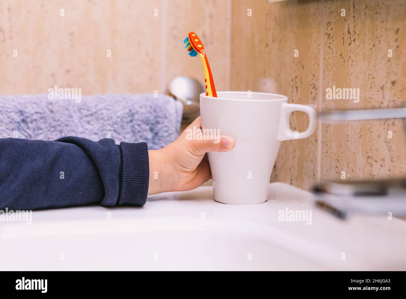 Detail of the arm of a little girl in the bathroom, clutching her cup ...