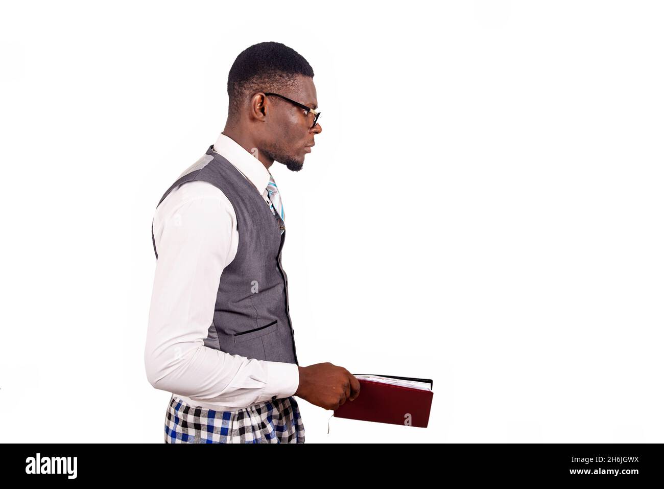 young businessman standing sideways wearing glasses holding a red diary ...