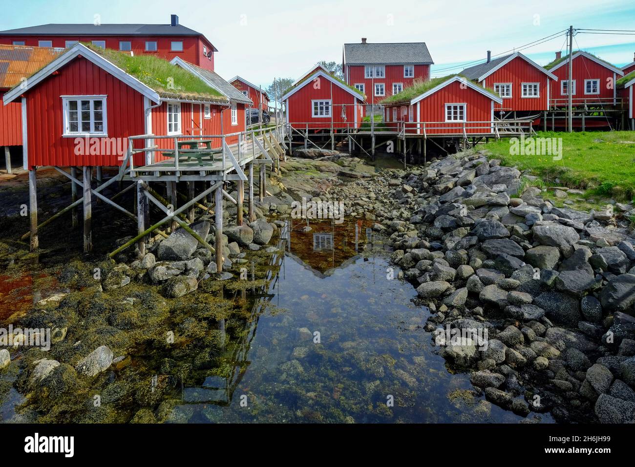 Red buildings grace the shoreline in the cod fishing village of Reine ...