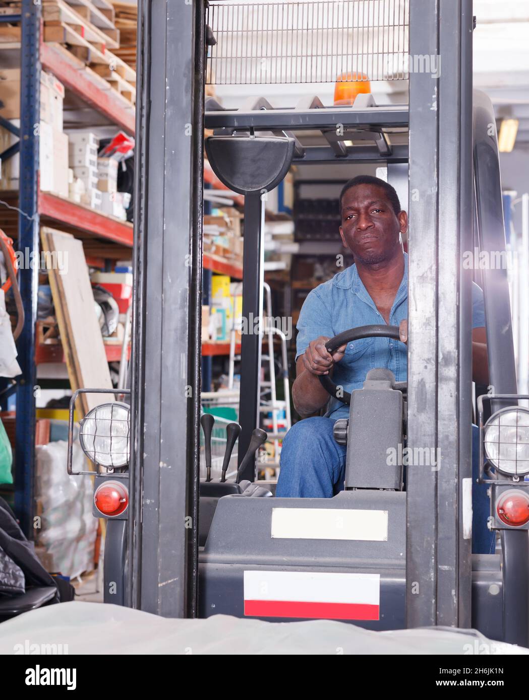 Glad male operator of forklift working in shop Stock Photo - Alamy