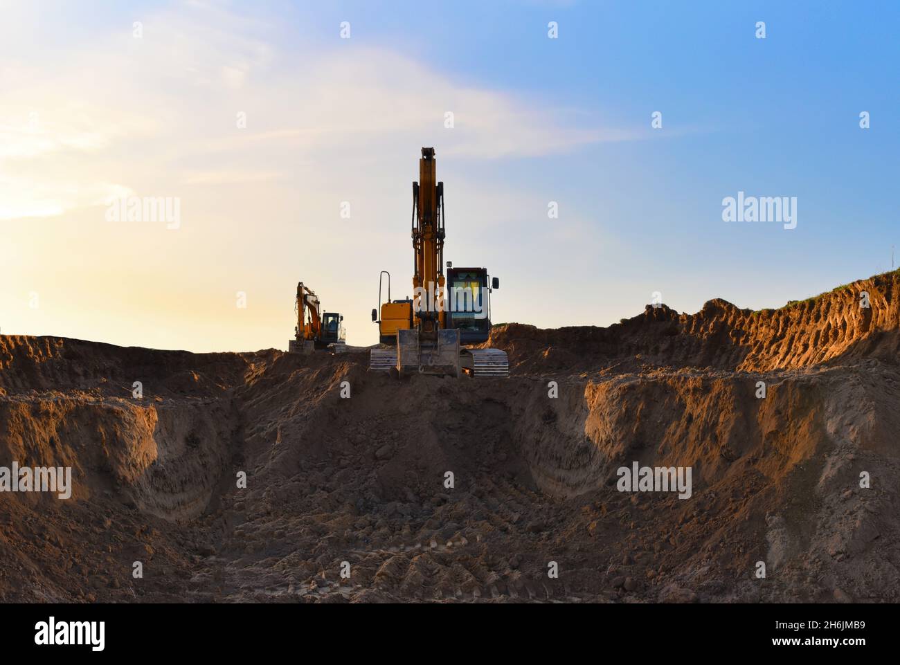 Excavator working on earthmoving at open pit mining on sunset ...