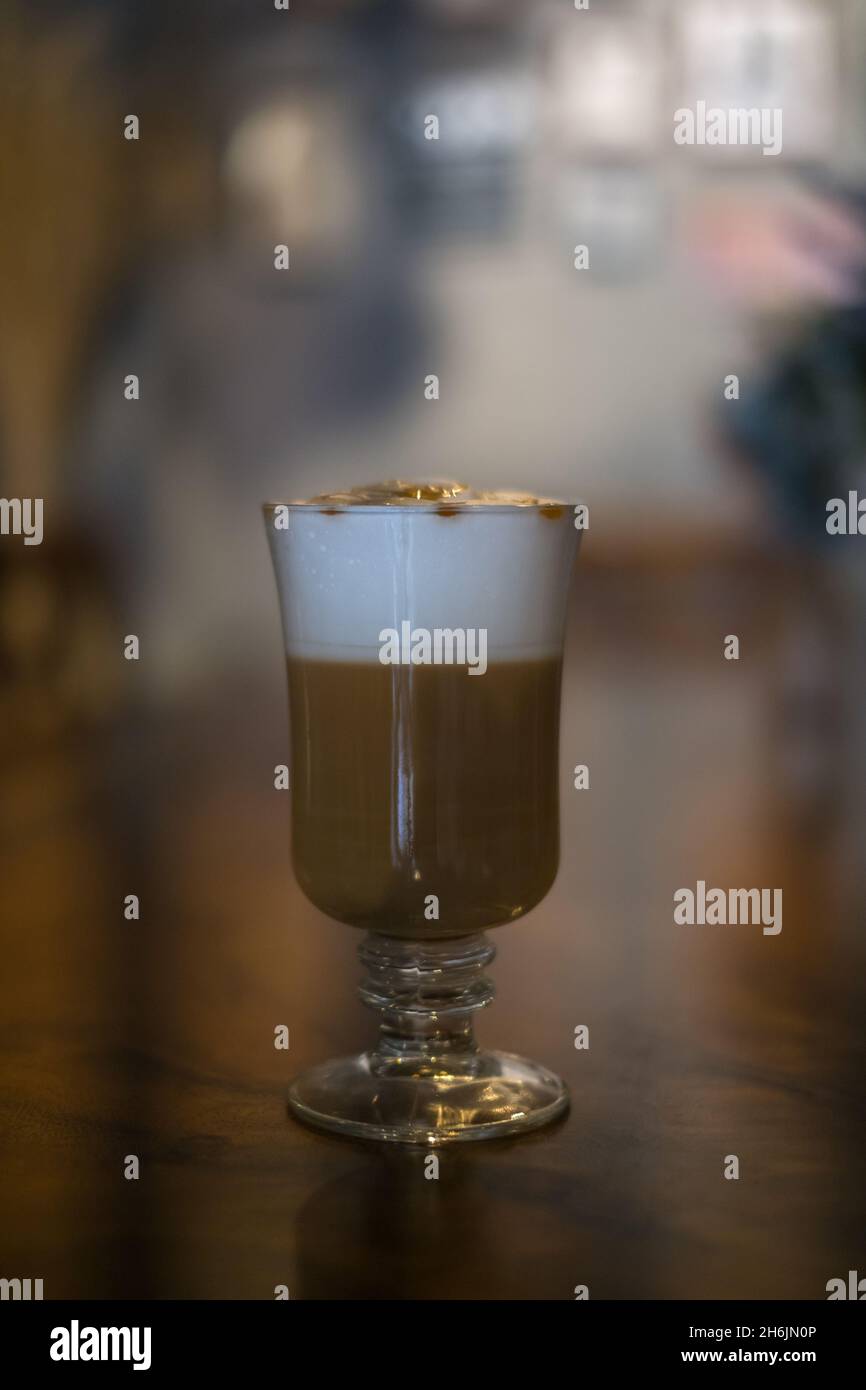 Glass cup with latte is on the table in coffee shop. Glass with caramel ...
