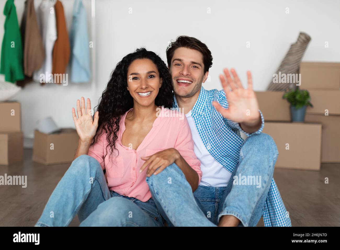 Happy couple waving hands to camera celebrating moving day Stock Photo ...