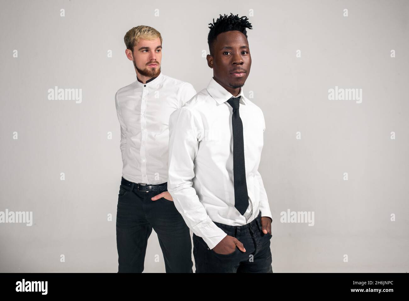 Friends. Two guys in white shirts and dark pants posing in the studio ...