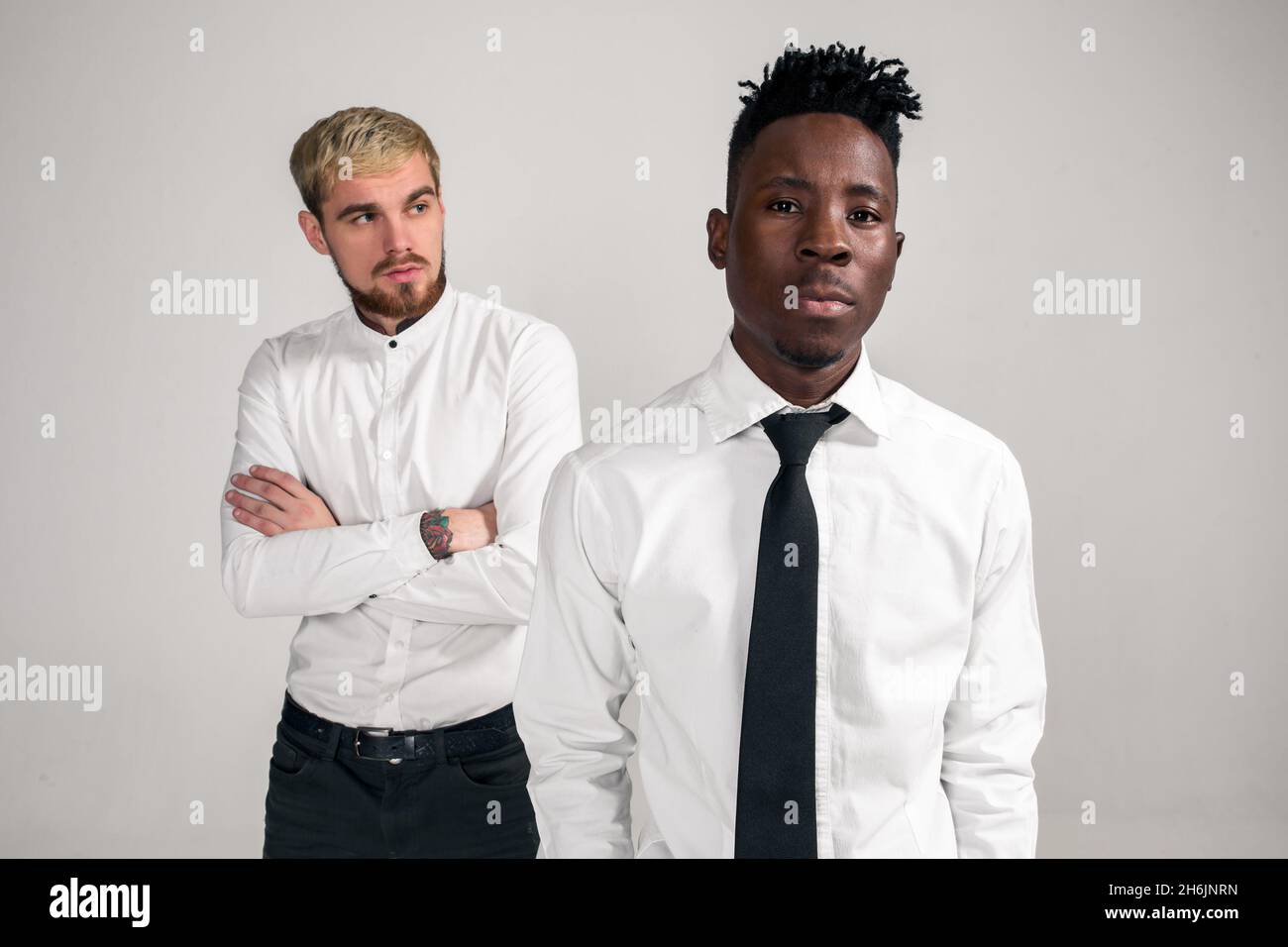 Friends. Two guys in white shirts and dark pants posing in the studio ...