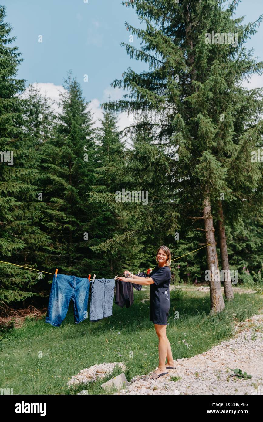 Young woman hangs clothes on clothesline outdoors in the courtyard of a ...