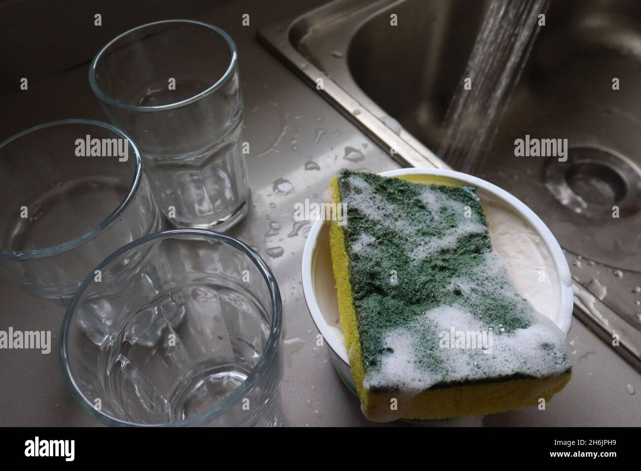 Washing the dishes while wasting water with opened tap, three cleaned ...