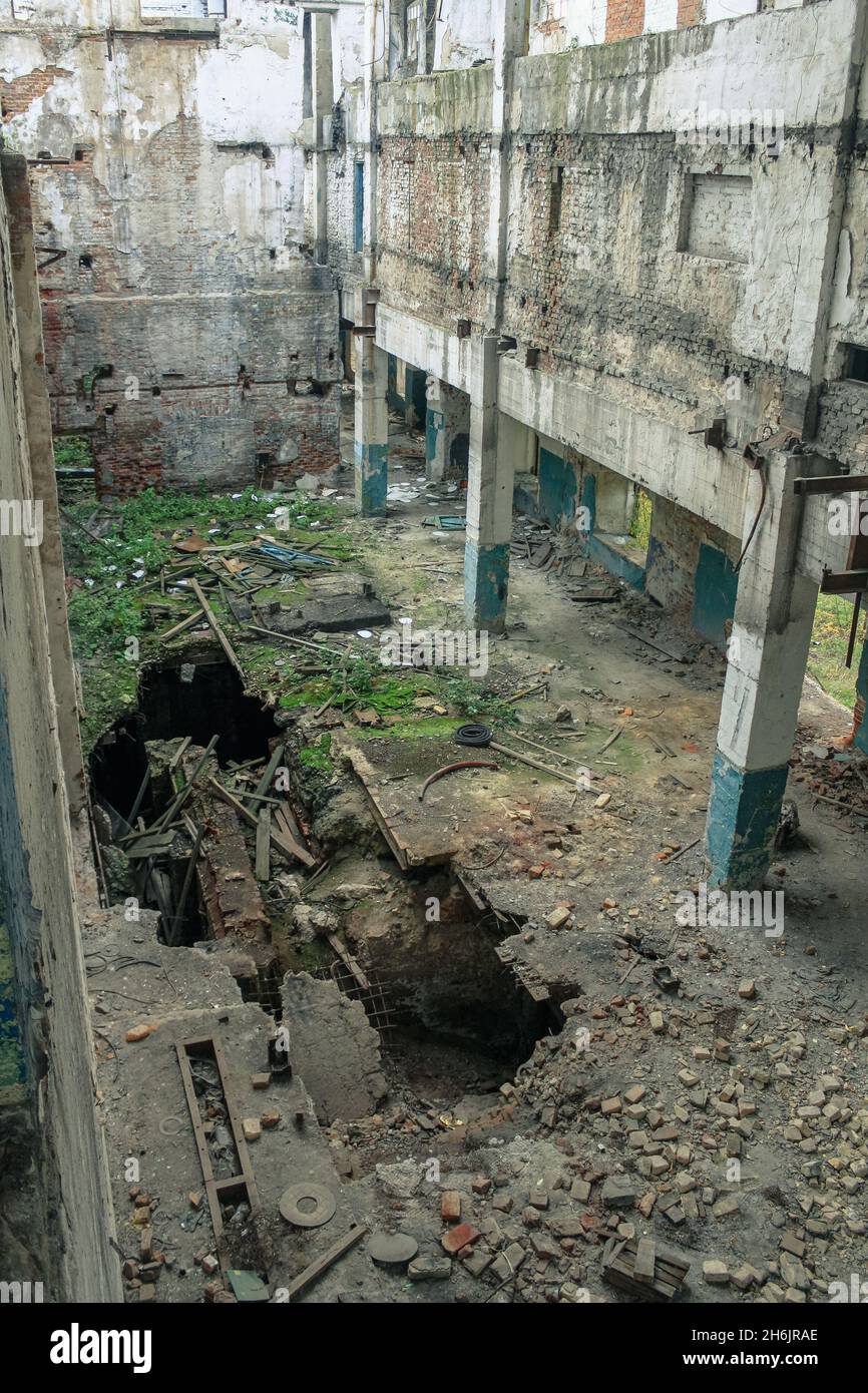 An abandoned factory with a collapsed floor. Peeling brick walls, wood ...
