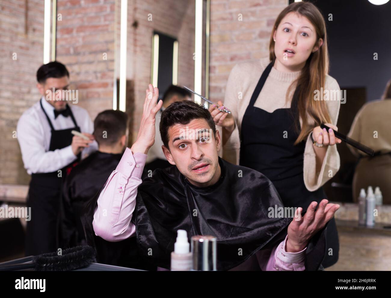 Shocked man with apologetic hairdresser at barbershop Stock Photo - Alamy