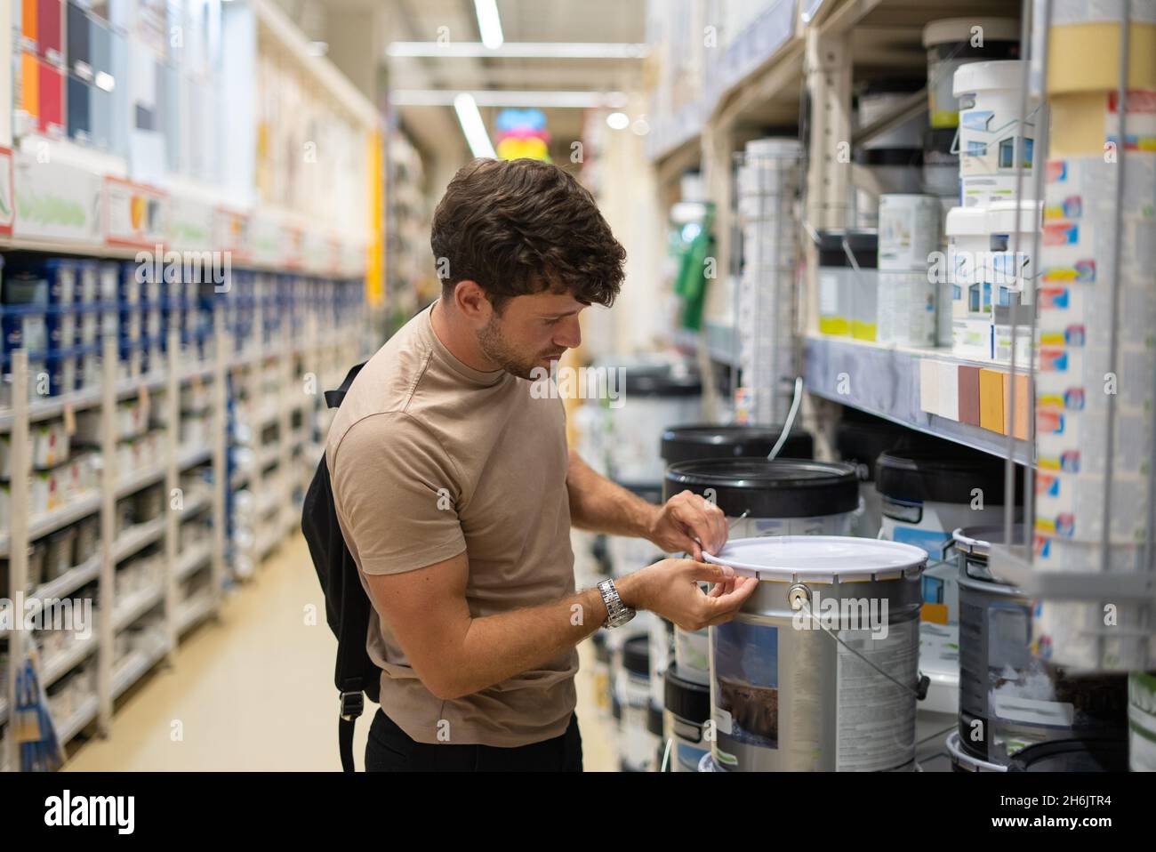 Male customer in beige t shirt opening bucket of paint while buying ...