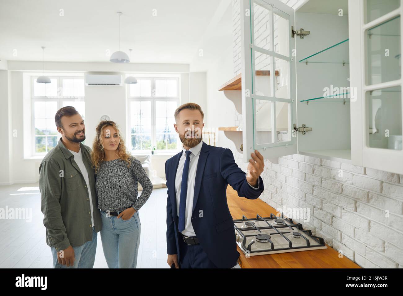 Real estate agent showing buyers kitchen cabinets while giving tour ...